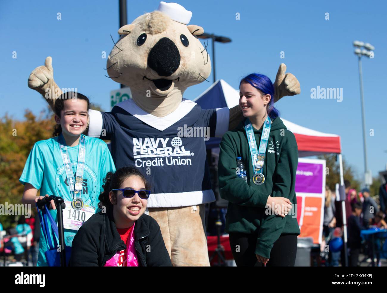 The Navy Federal Credit Union mascot takes a photo with runners during ...