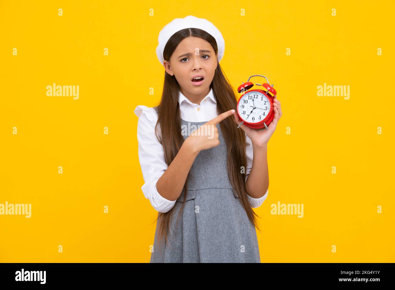 Teenager child hold clock isolated on yellow studio background ...