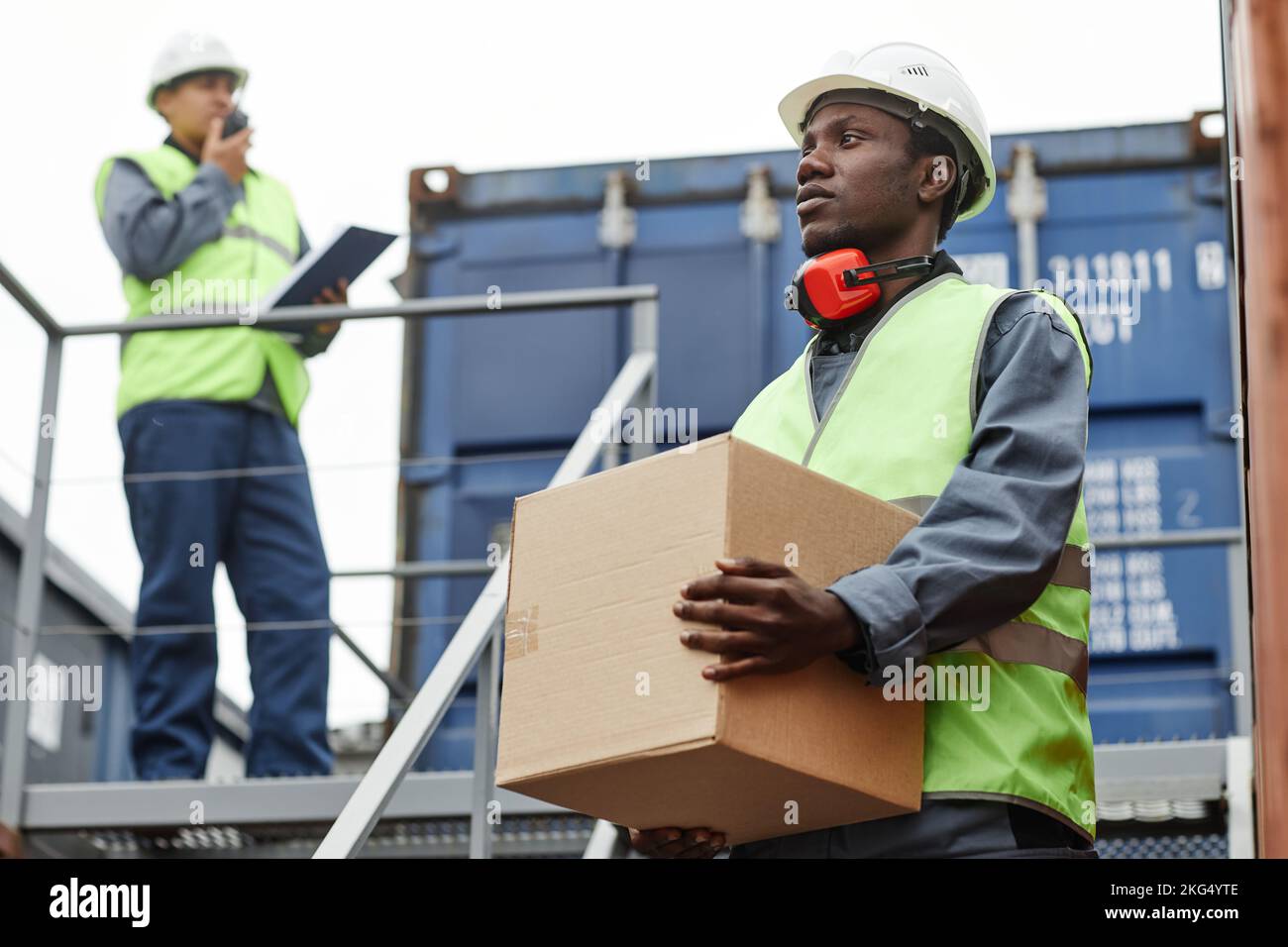 Waist up portrait of male African American worker carrying boxes up ...