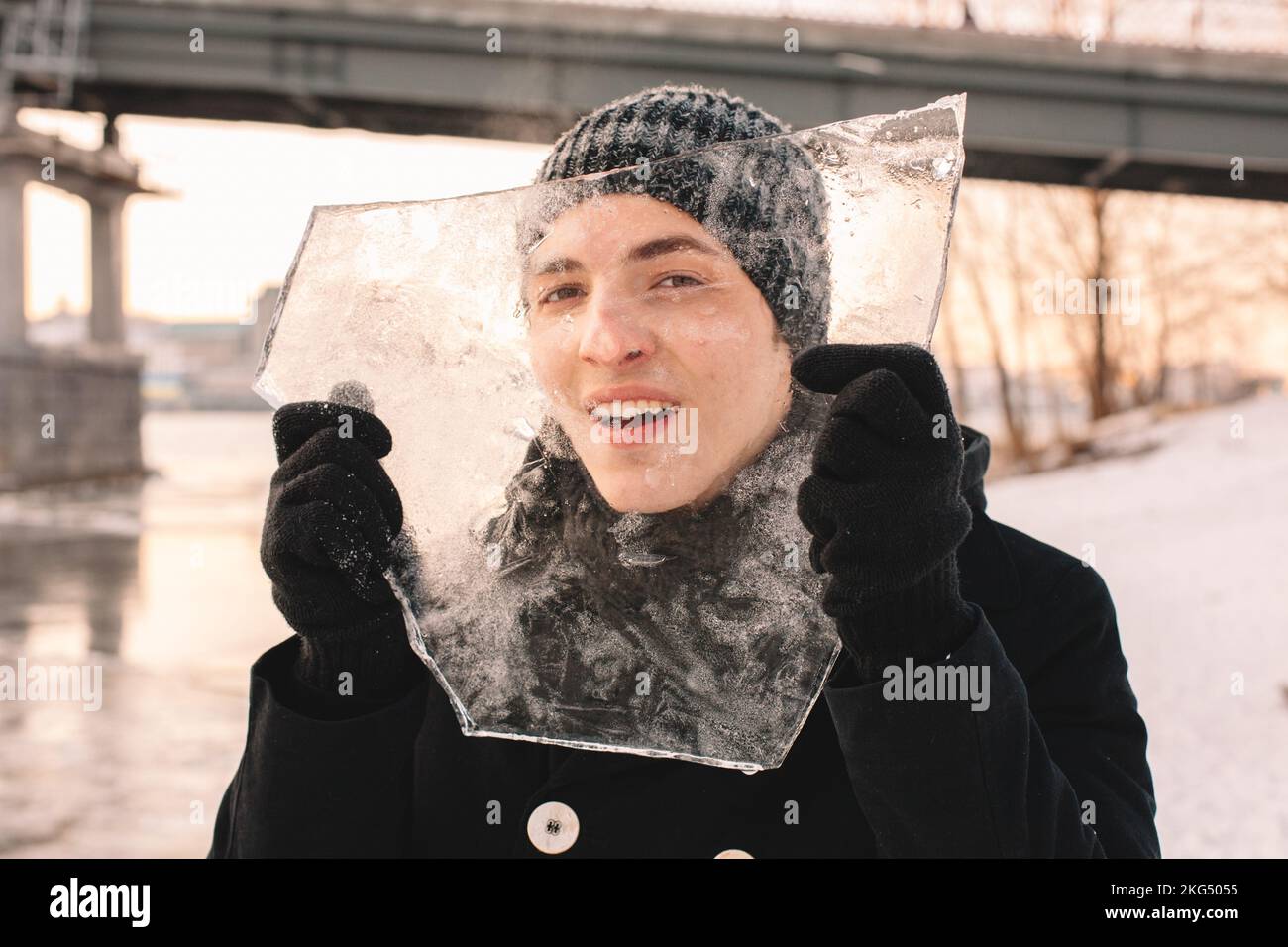 Teenage boy holding chunk of ice in front of his face and looking ...