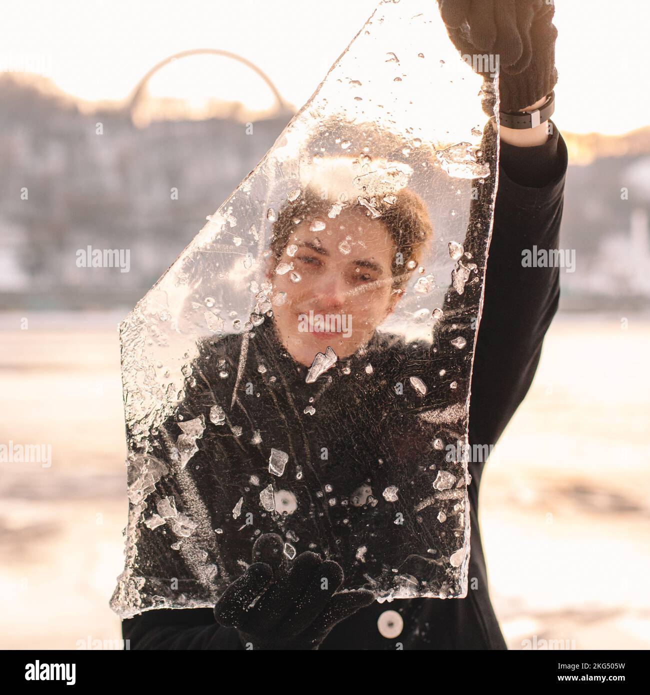 Happy teenage boy looking through chunk of ice while holding it ...