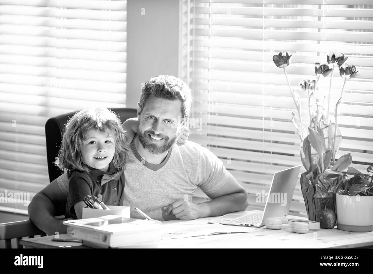 happy father helping his school child study with writing and laptop ...