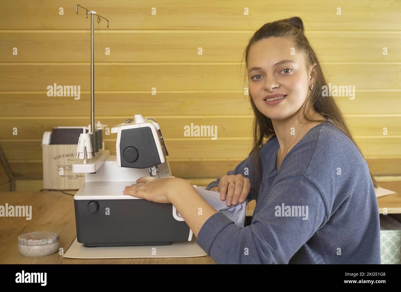 A woman designer works on an overlock sewing machine on tailoring. Small tailoring business ...