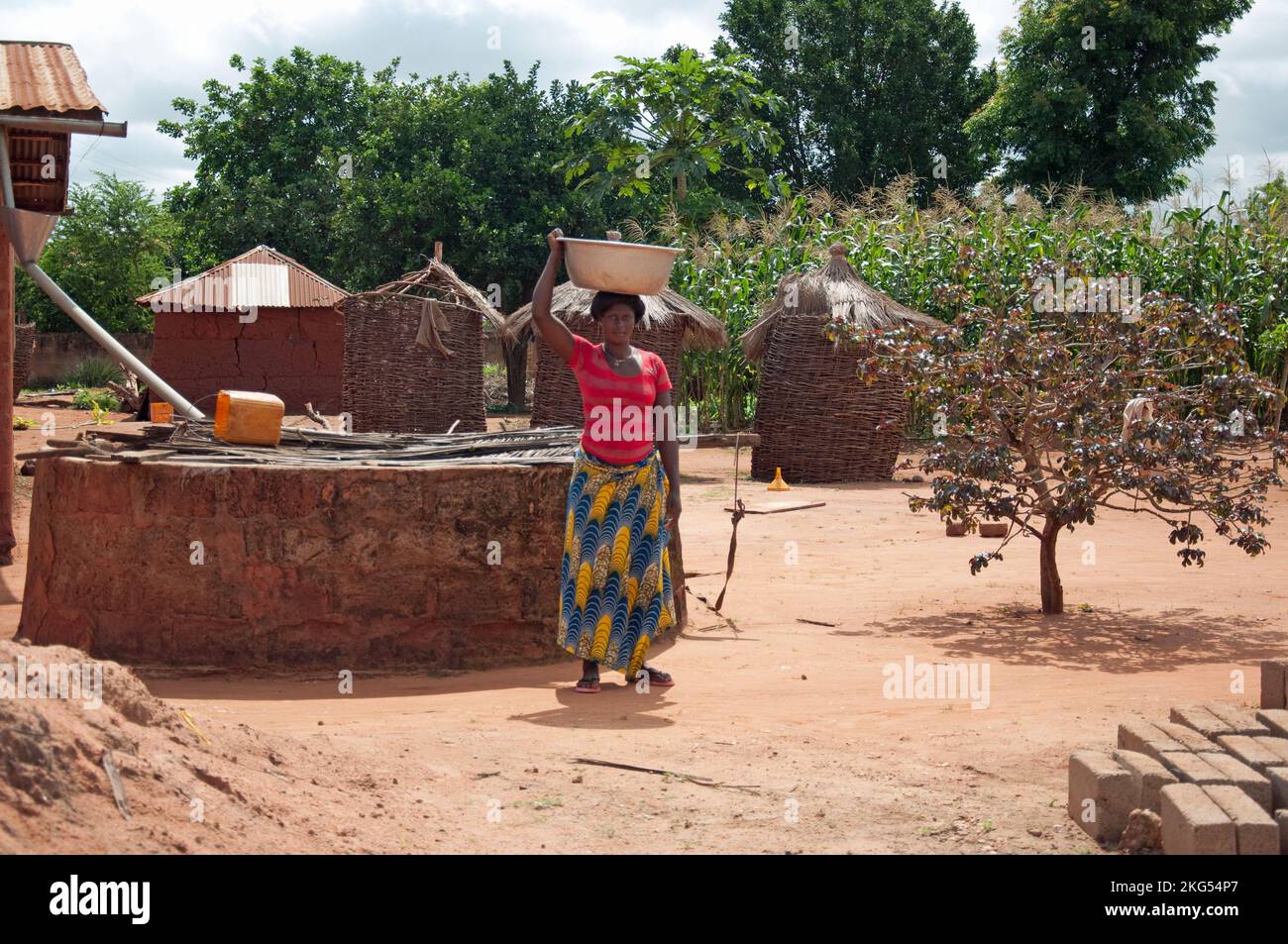African courtyard, Adjahonme, Couffo, Benin, woman carrying water on ...