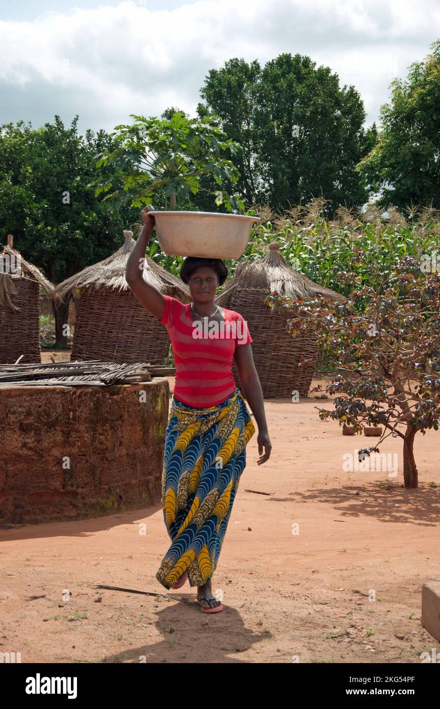 African courtyard, Adjahonme, Couffo, Benin - woman carrying water on ...