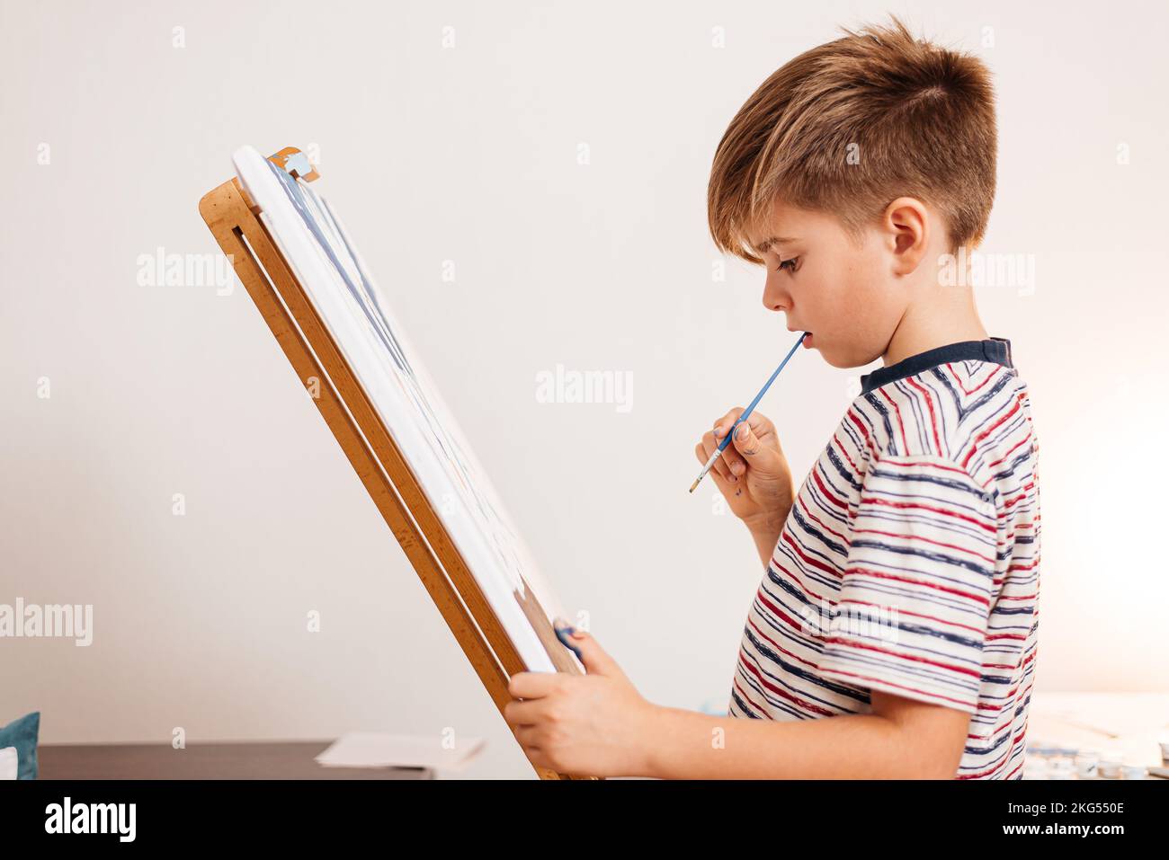 A boy paints a picture on an easel and paints Stock Photo - Alamy