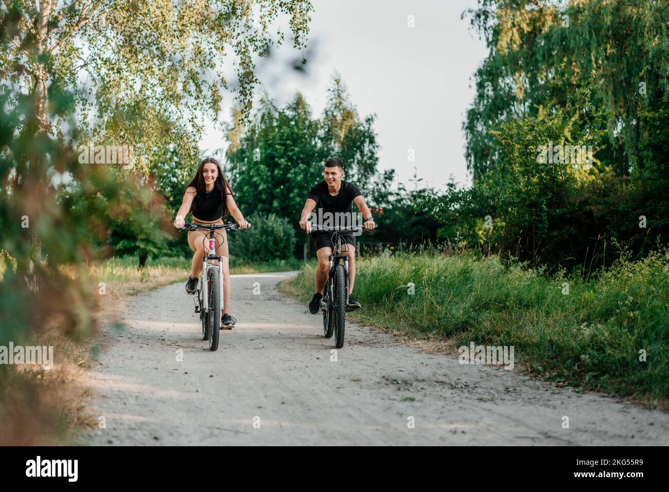 Happy couple racing on a bike along the sand and grass high in the ...