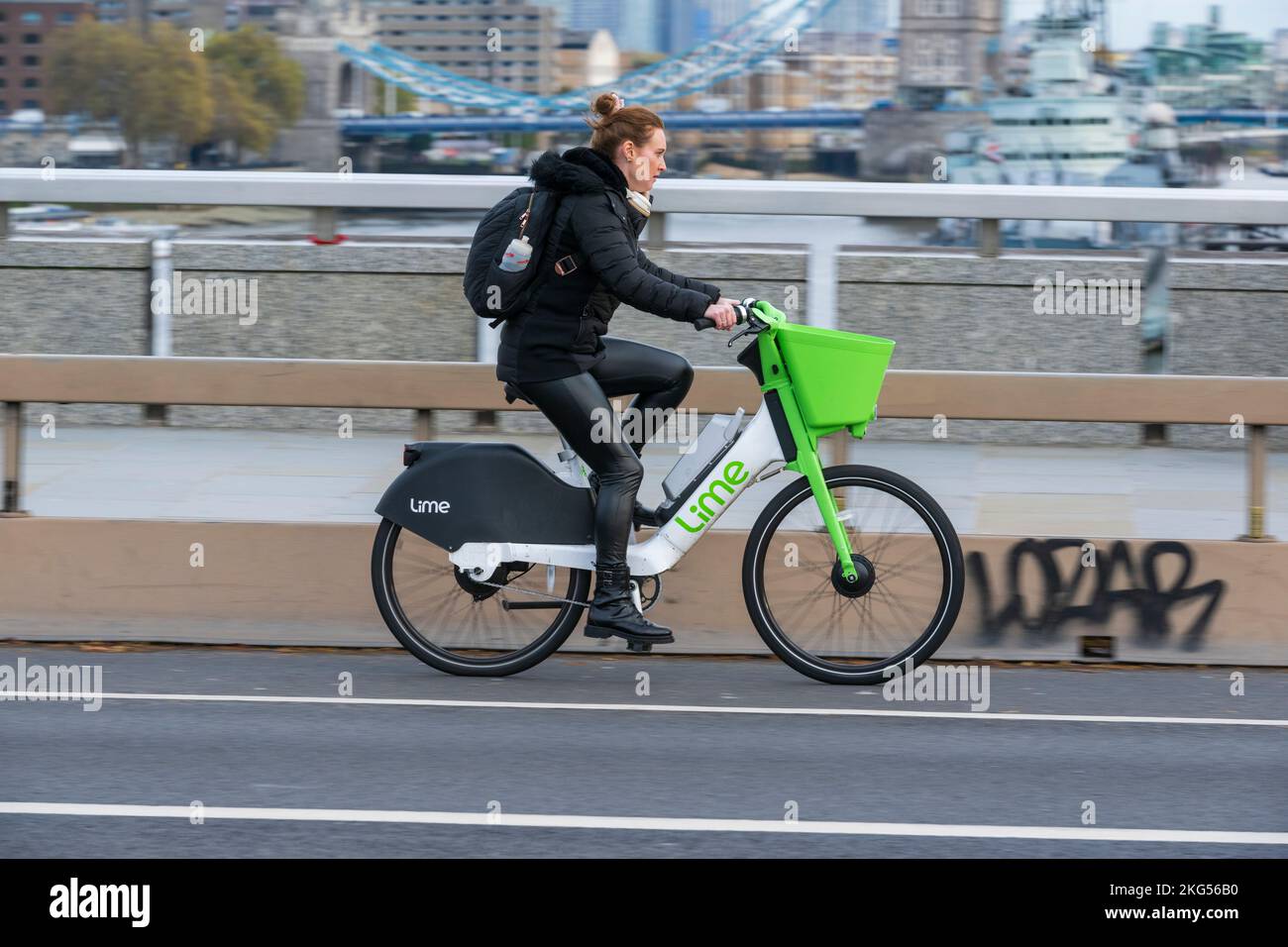 A woman commuting on a Lime electric hire bike across London Bridge during the rush hour. London ...