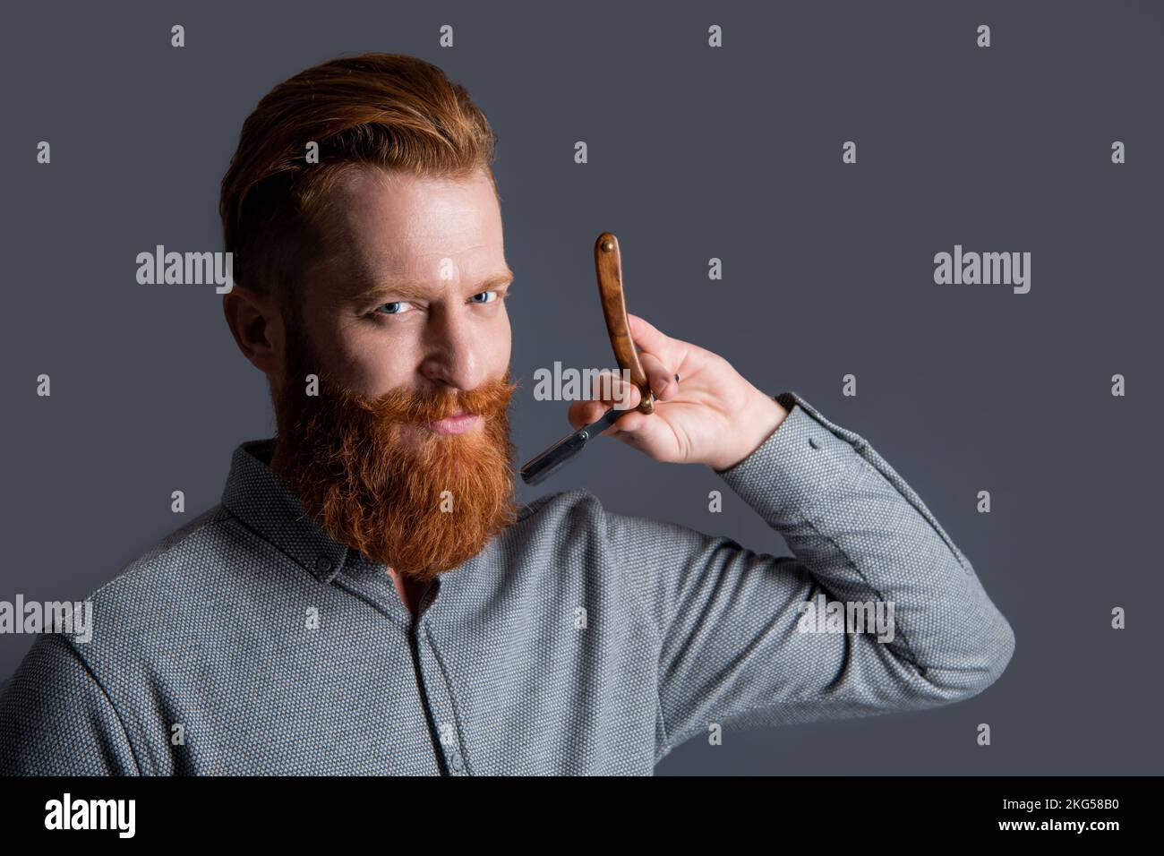 positive man in barbershop studio. man hold barbershop blade to shave ...