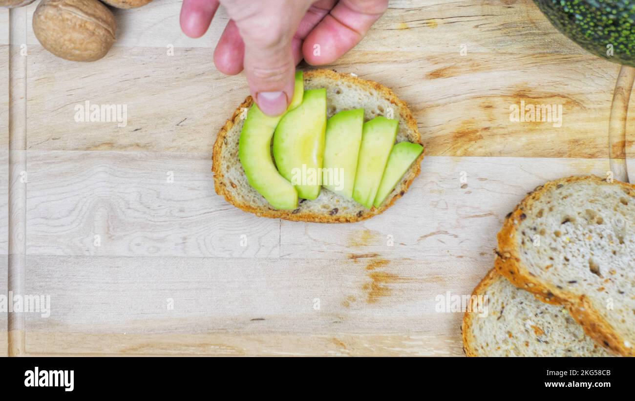 Woman making avocado peanut butter toast for a healthy breakfast at ...