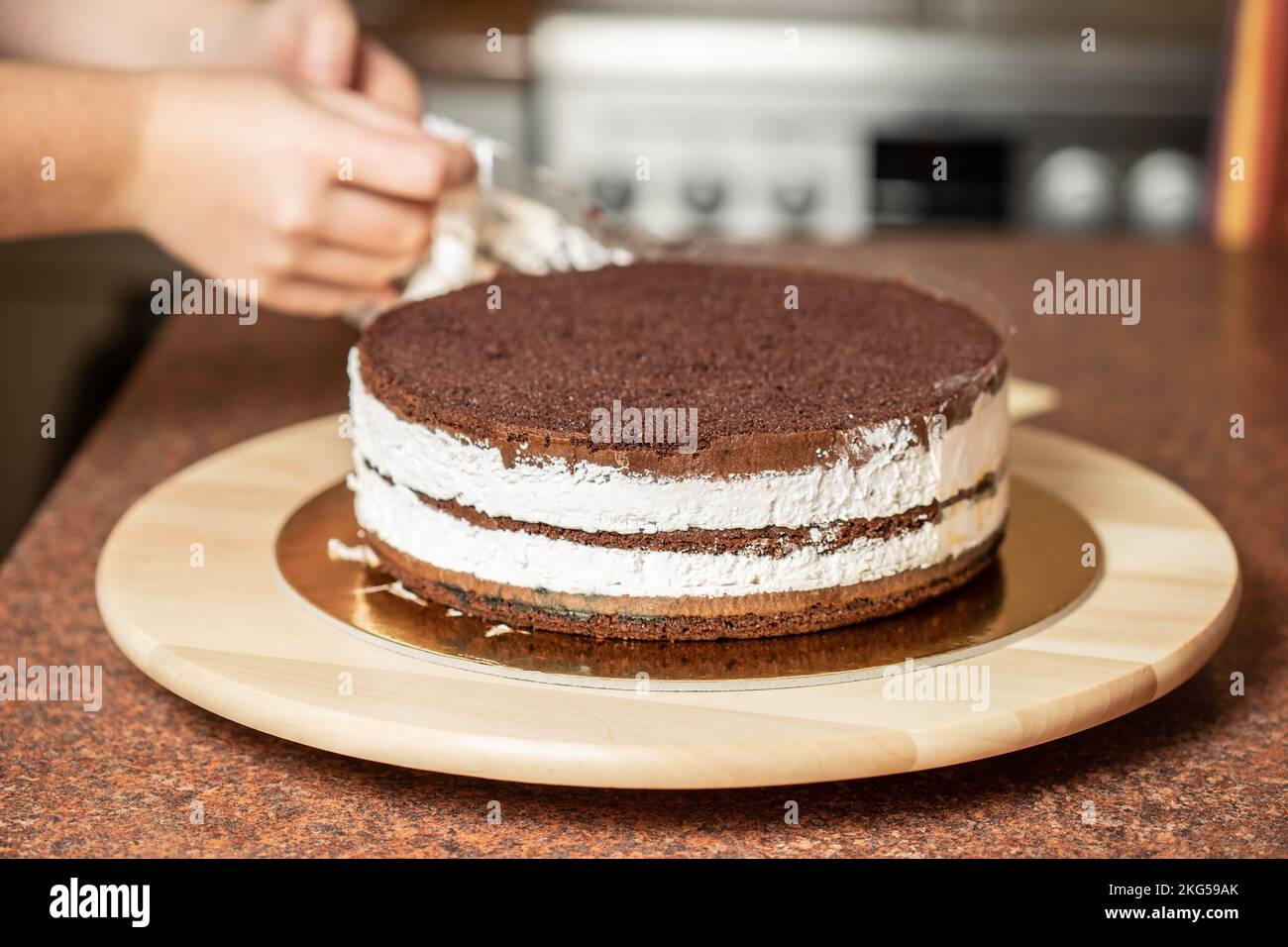 A caucasian woman decorating a freshly chocolate baked cake in the ...