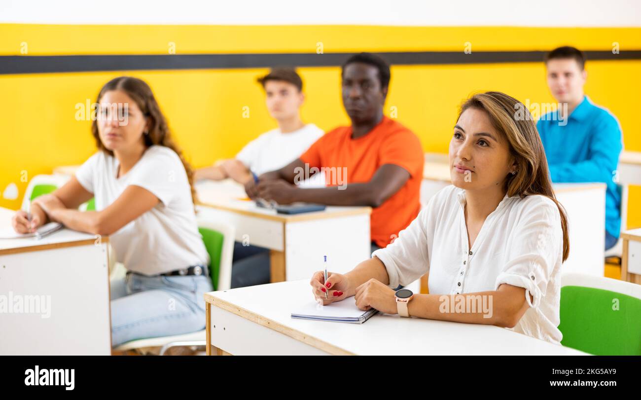 Portrait of focused female studying in classroom with colleagues Stock ...