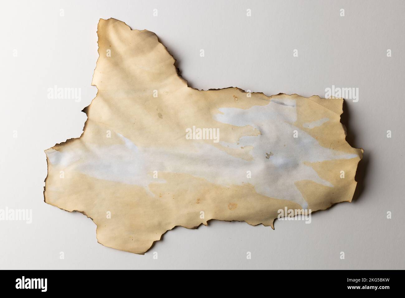 Burned and stained piece of paper with copy space on white background ...