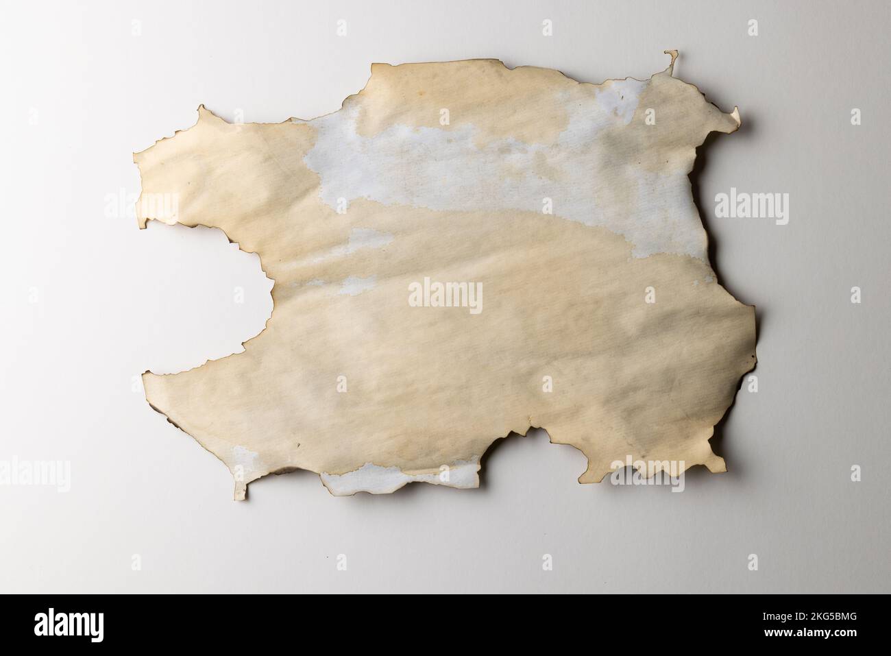 Burned and stained piece of paper with copy space on white background ...