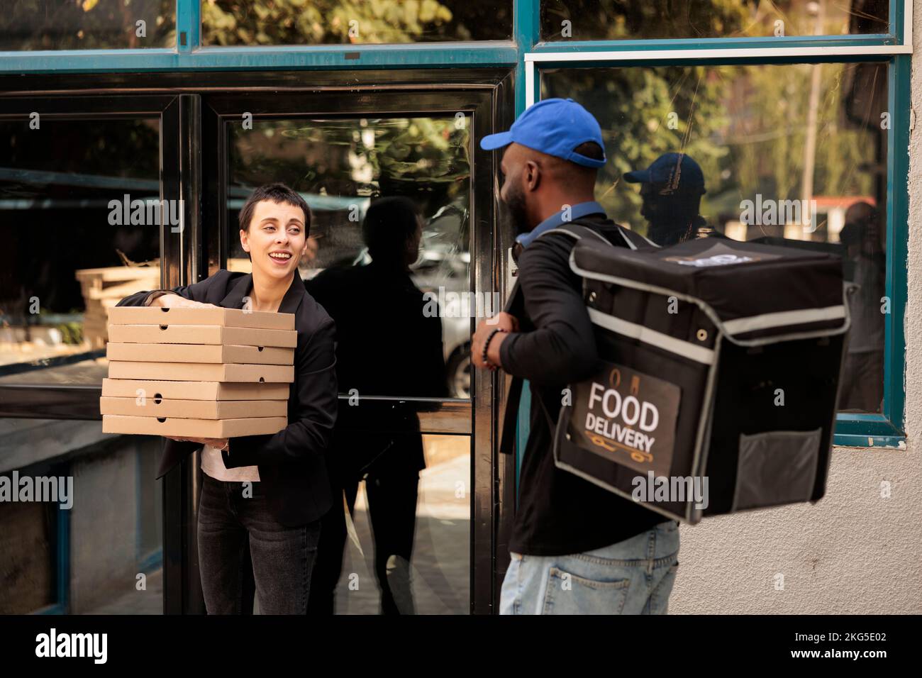 Smiling customer receiving pizza order from courier outdoors, woman ...