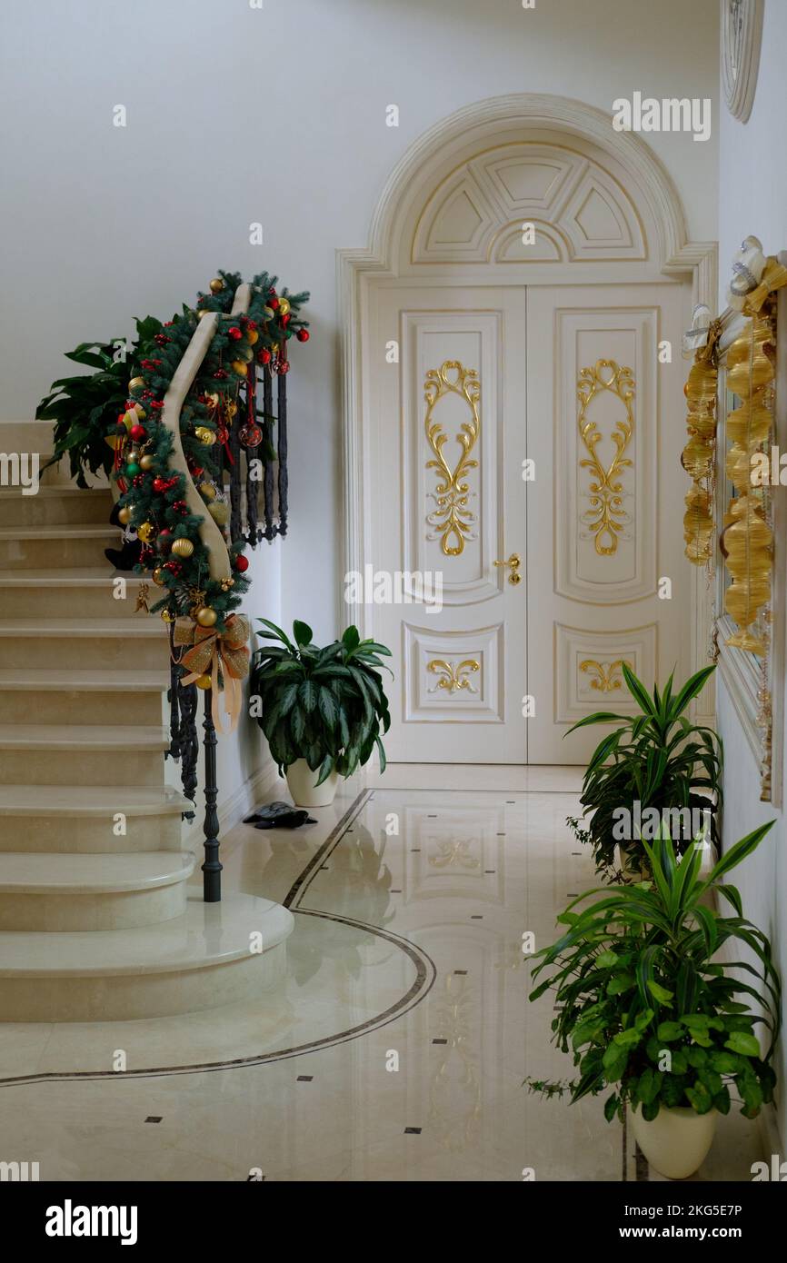 Christmas decorations in the hall of luxurious home with marble stairs ...