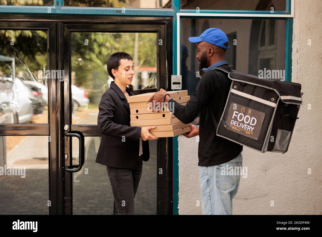 Pizzeria courier giving customer pizza order outdoors, woman taking ...