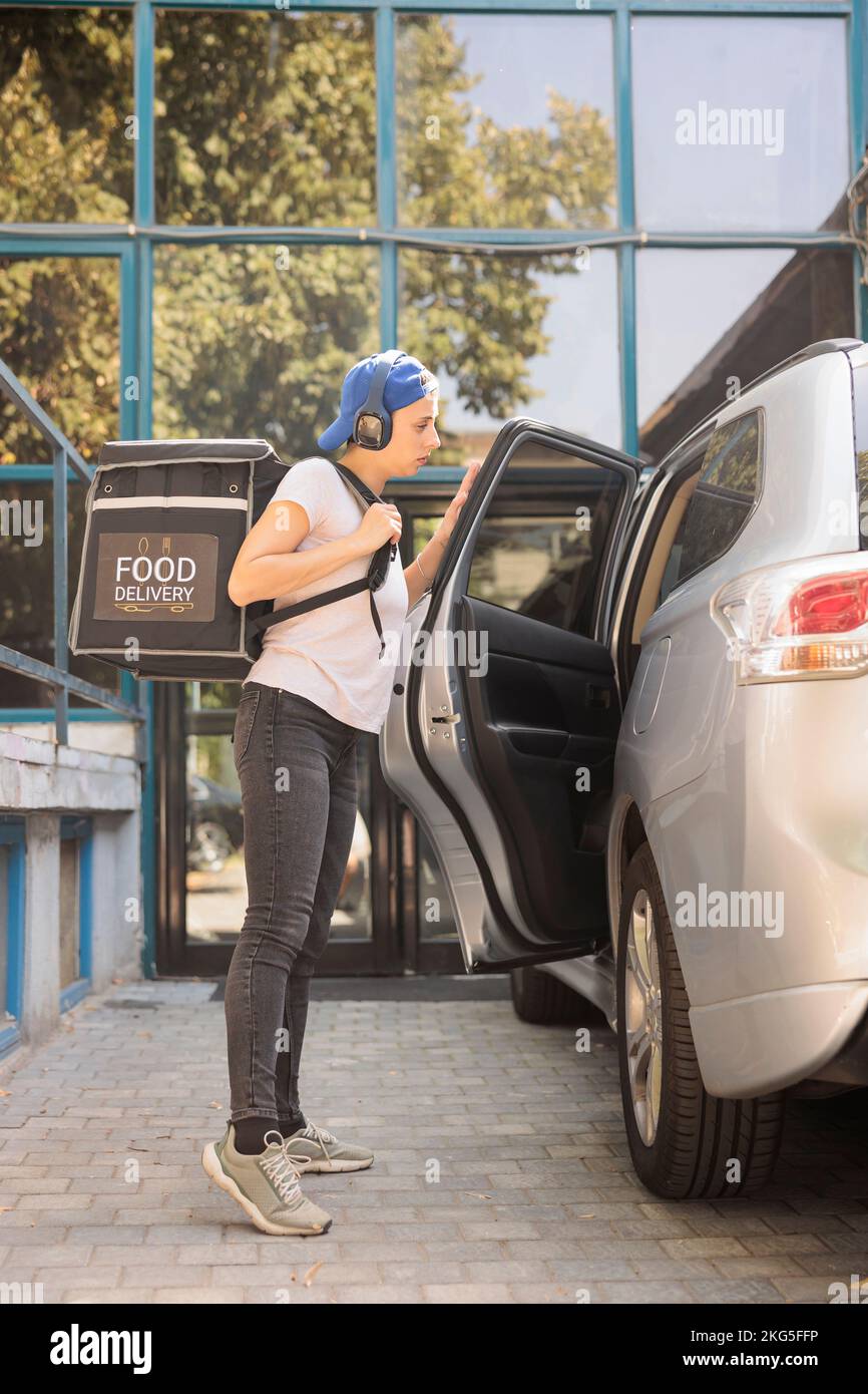 Office lunch delivery service courier delivering food by car, holding ...