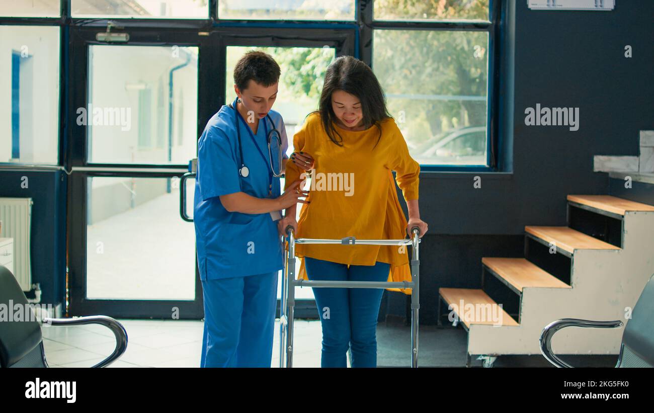 Female nurse helping patient with leg injury to use walk frame, dealing ...