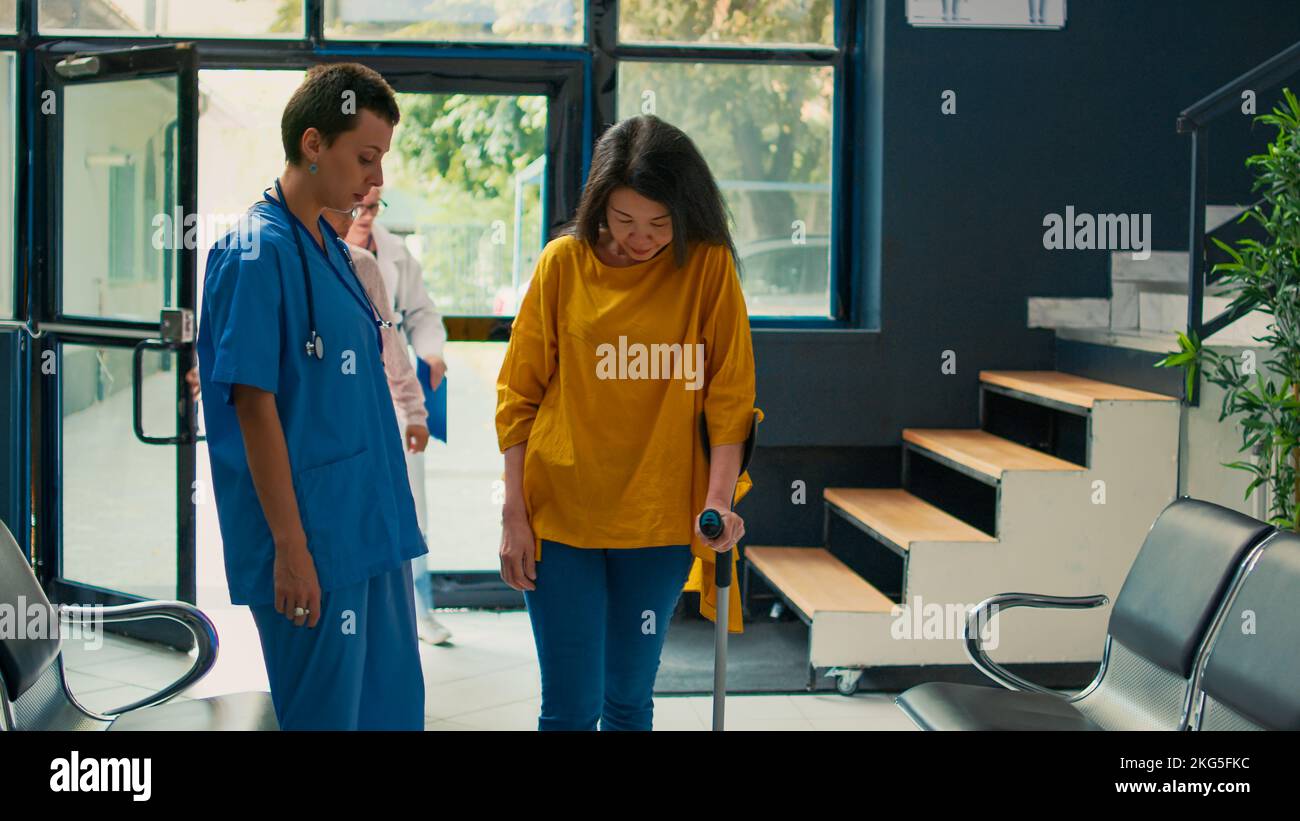 Medical assistant helping asian woman to walk with stick, suffering ...