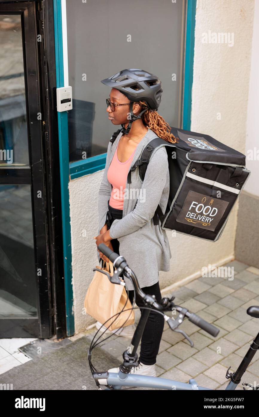 Woman on bike delivering food, waiting for customer near office ...