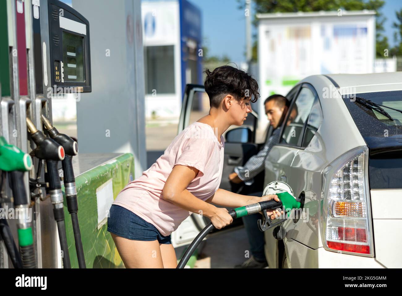 Latin woman filling up tank of her car with gasoline in gas station ...