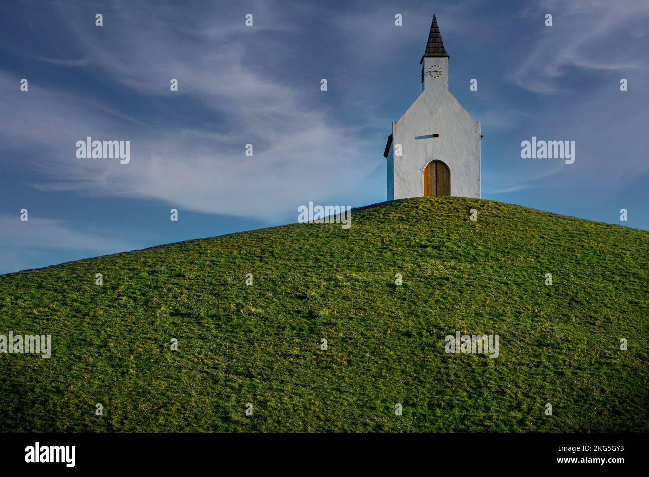 A low angle shot of a small church on a rural green hill in the ...