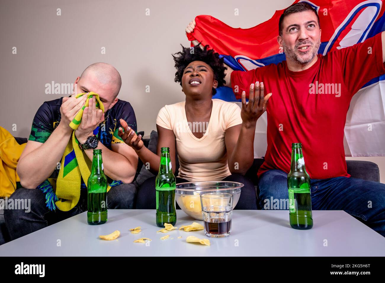 Friends watching a football match on TV, cheering for their national ...