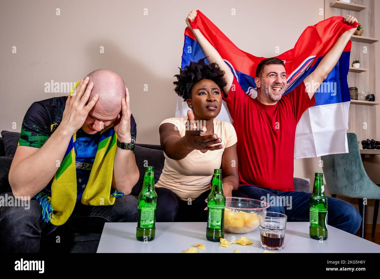 Friends watching a football match on TV, cheering for their national ...