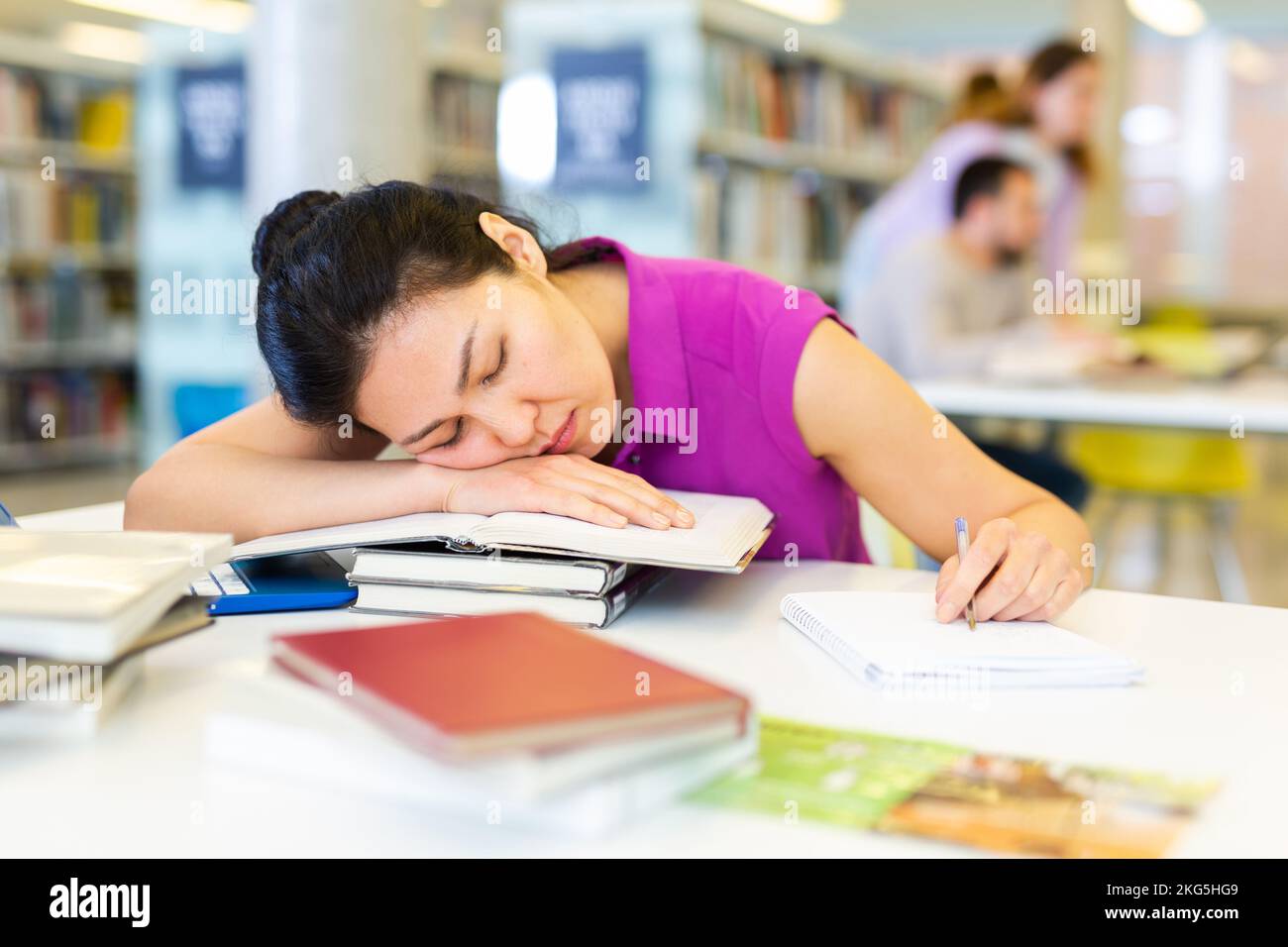 Woman resting her head on stack of books in public library Stock Photo ...