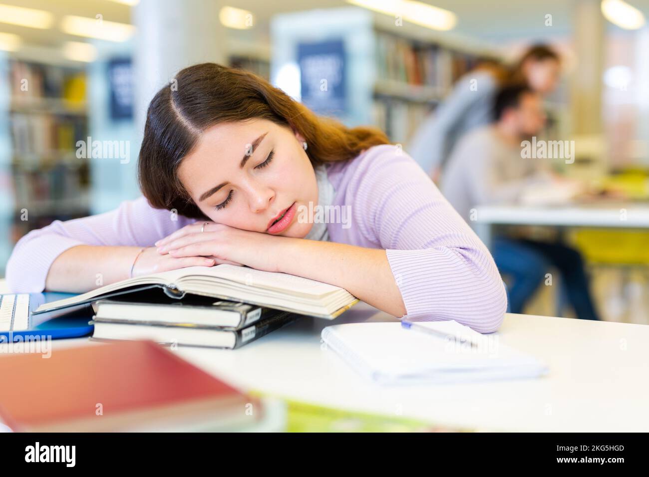 Tired woman sleeping on books at library Stock Photo - Alamy
