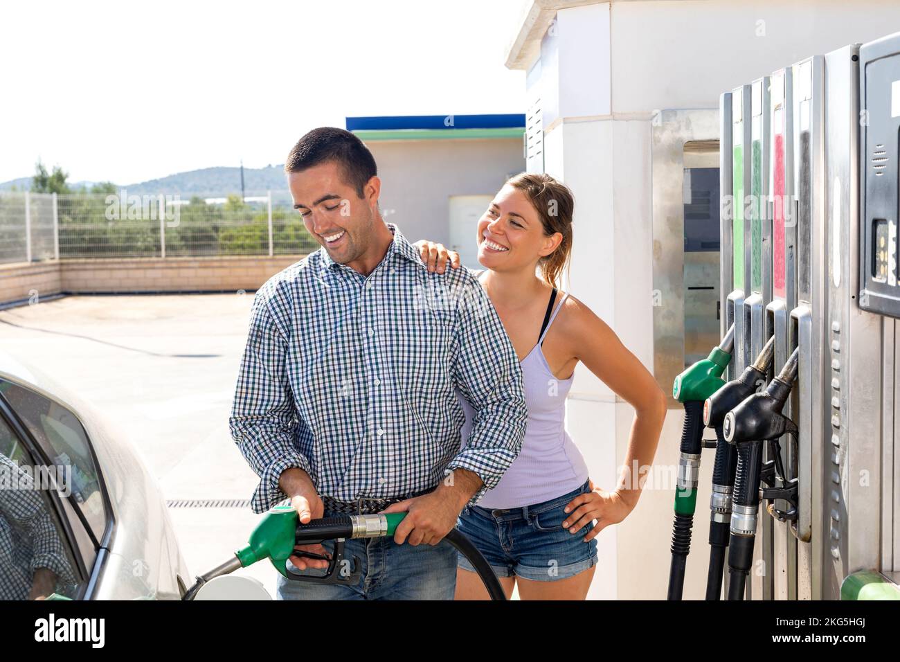 Positive couple filling up tank of their car with gasoline in gas ...