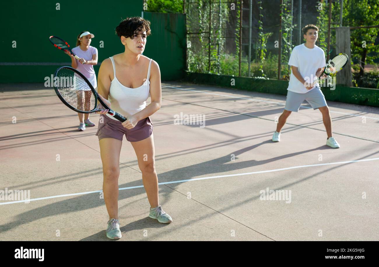 Young hispanic female frontenis player swinging racquet to hit ball ...