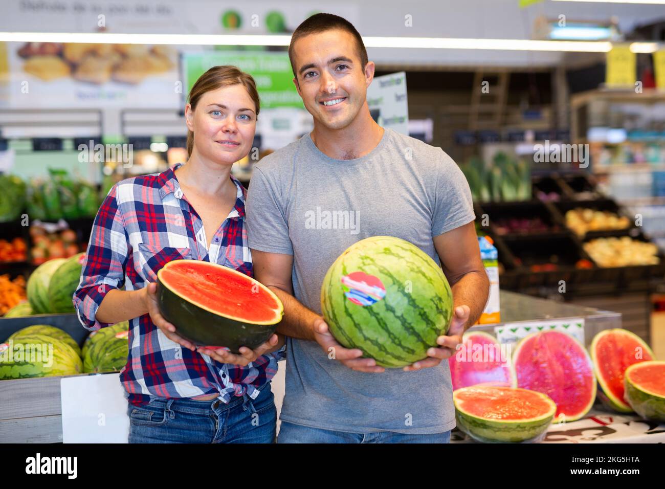 Positive couple choosing watermelon in fruit and vegetable section of ...