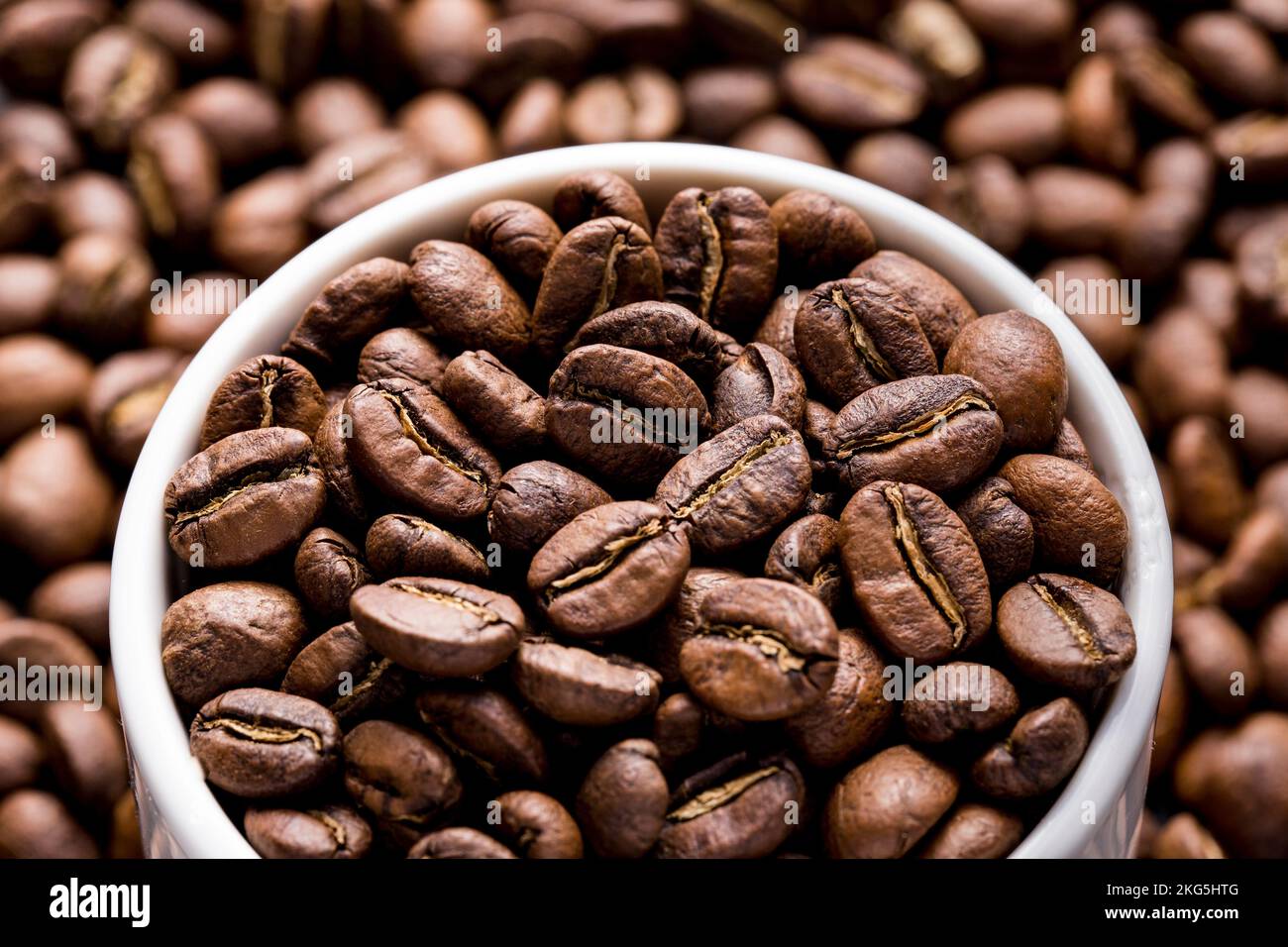 Roasted coffee beans in a cup, on dark background, close-up image ...