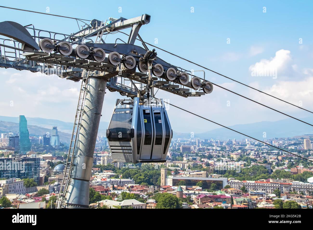 Closeup of cable car over the roofs of Tbilisi Georgia with city spread ...