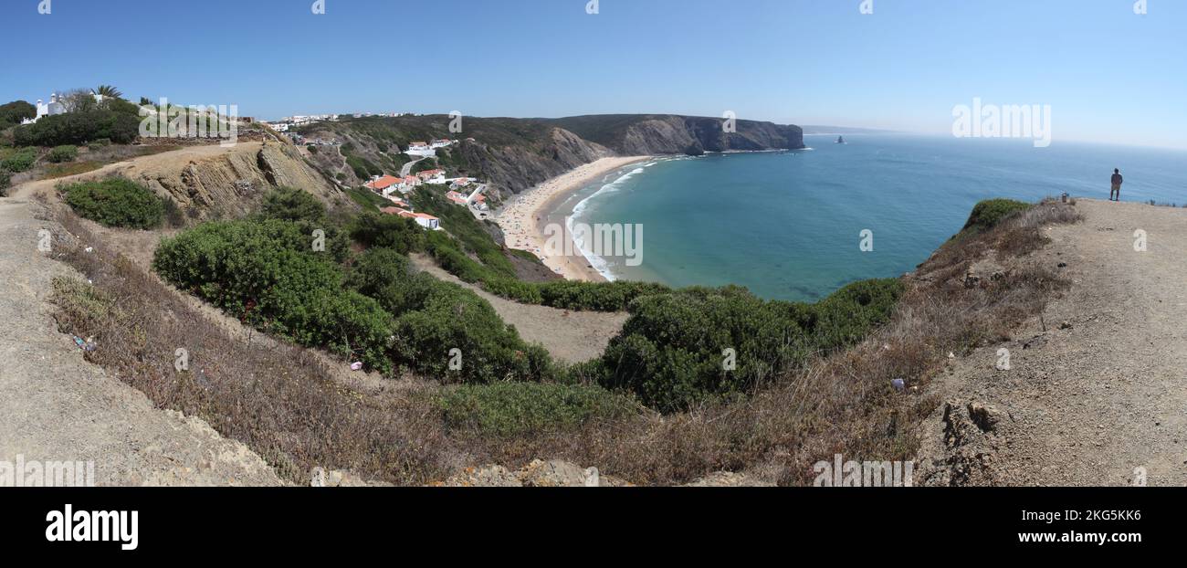 A panoramic view of a person standing alone on a cliff and watching the ...