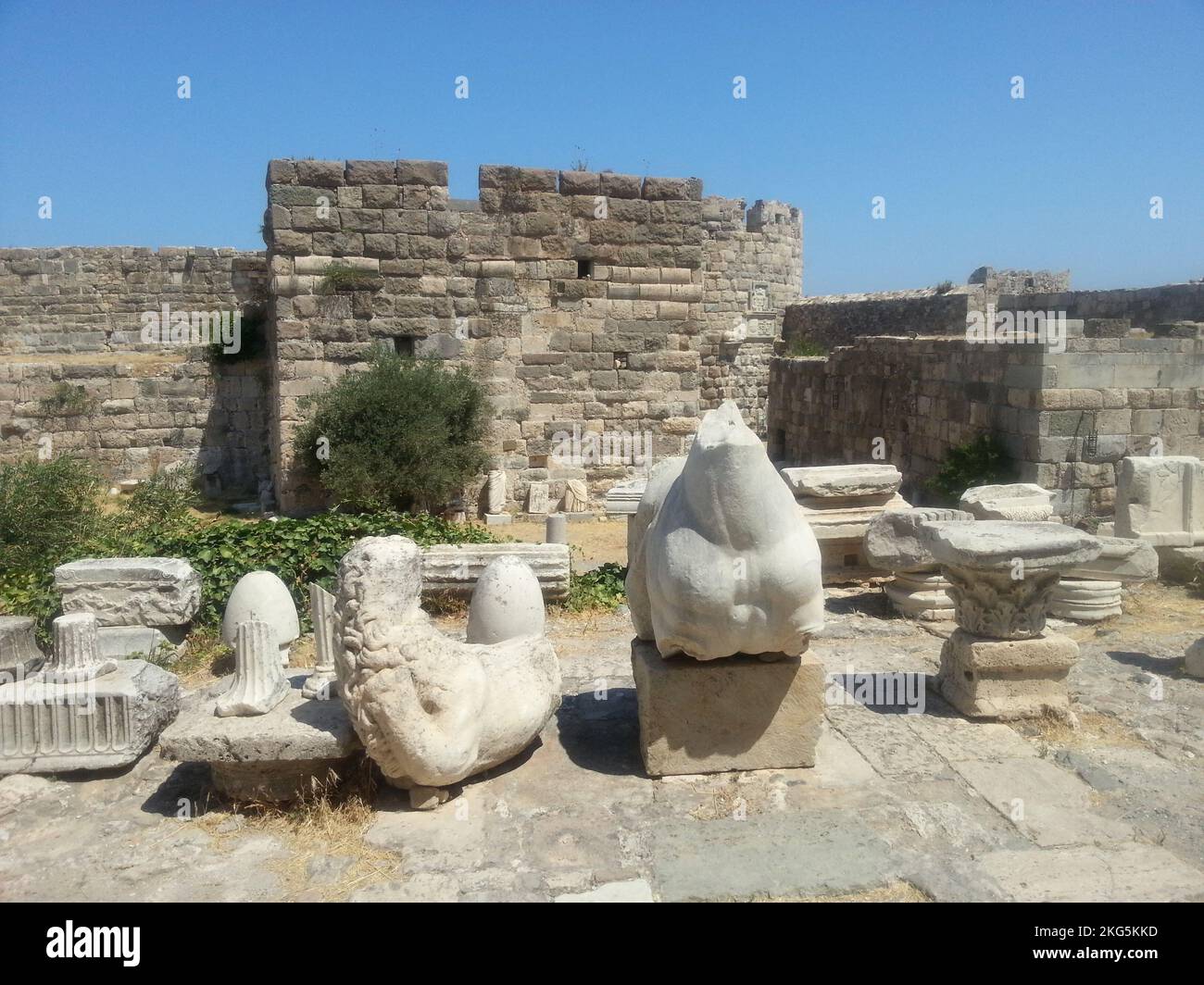 A ruins against old stony wall on a sunny day, damaged marble statues ...