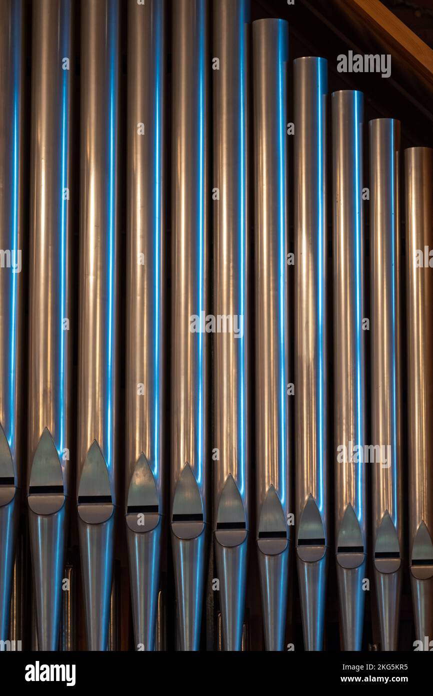 A vertical closeup shot of metal musical organ tubes hung on a wall ...