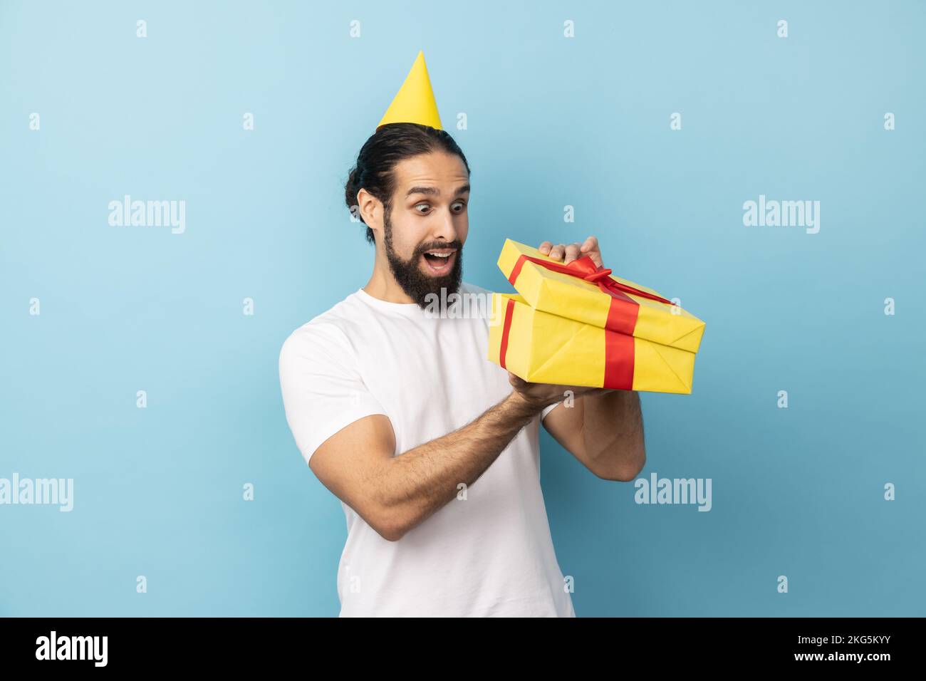 Portrait of man with beard wearing white T-shirt and party cone ...