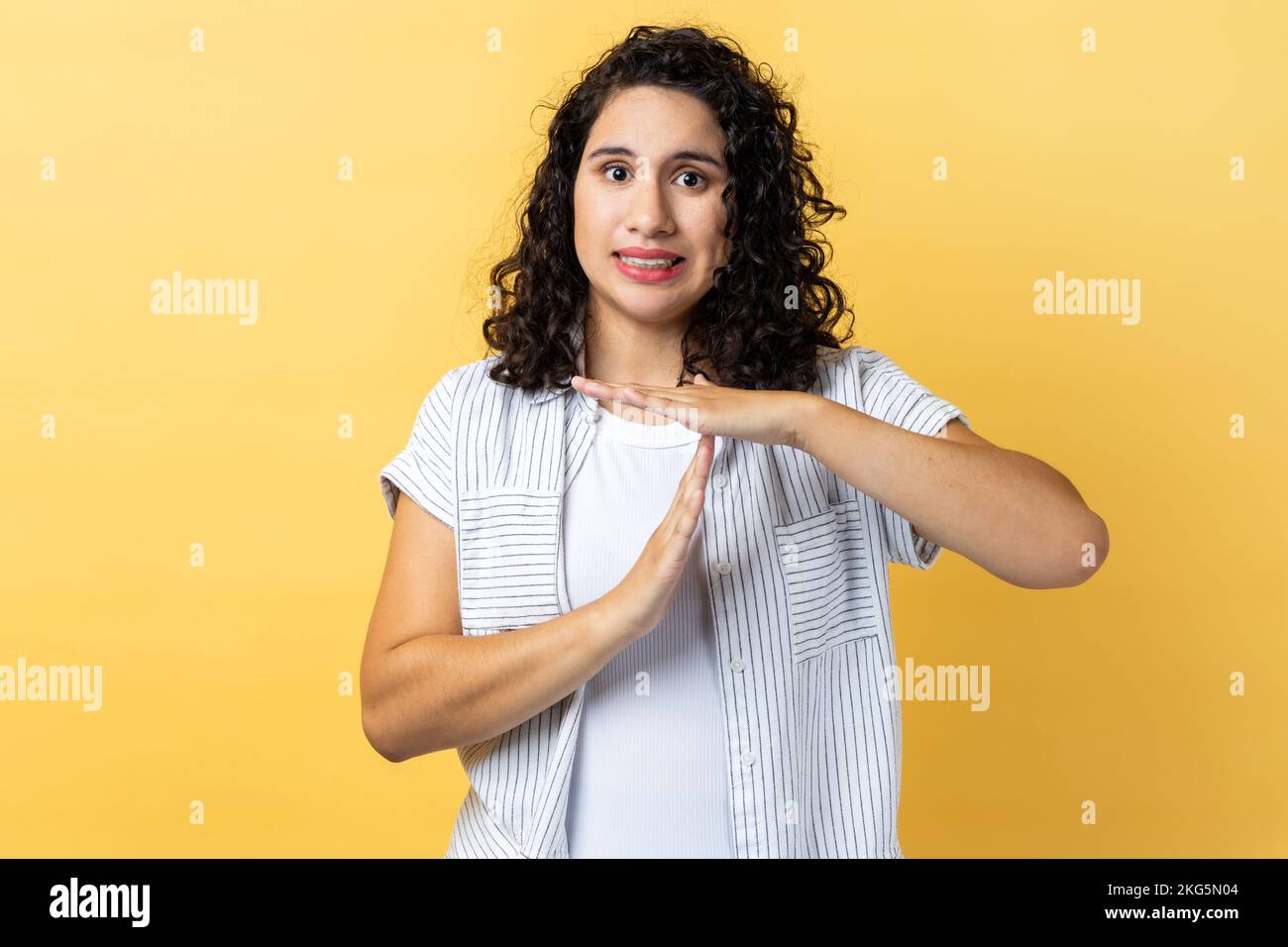 Portrait of bossy serious woman with dark wavy hair showing time out ...