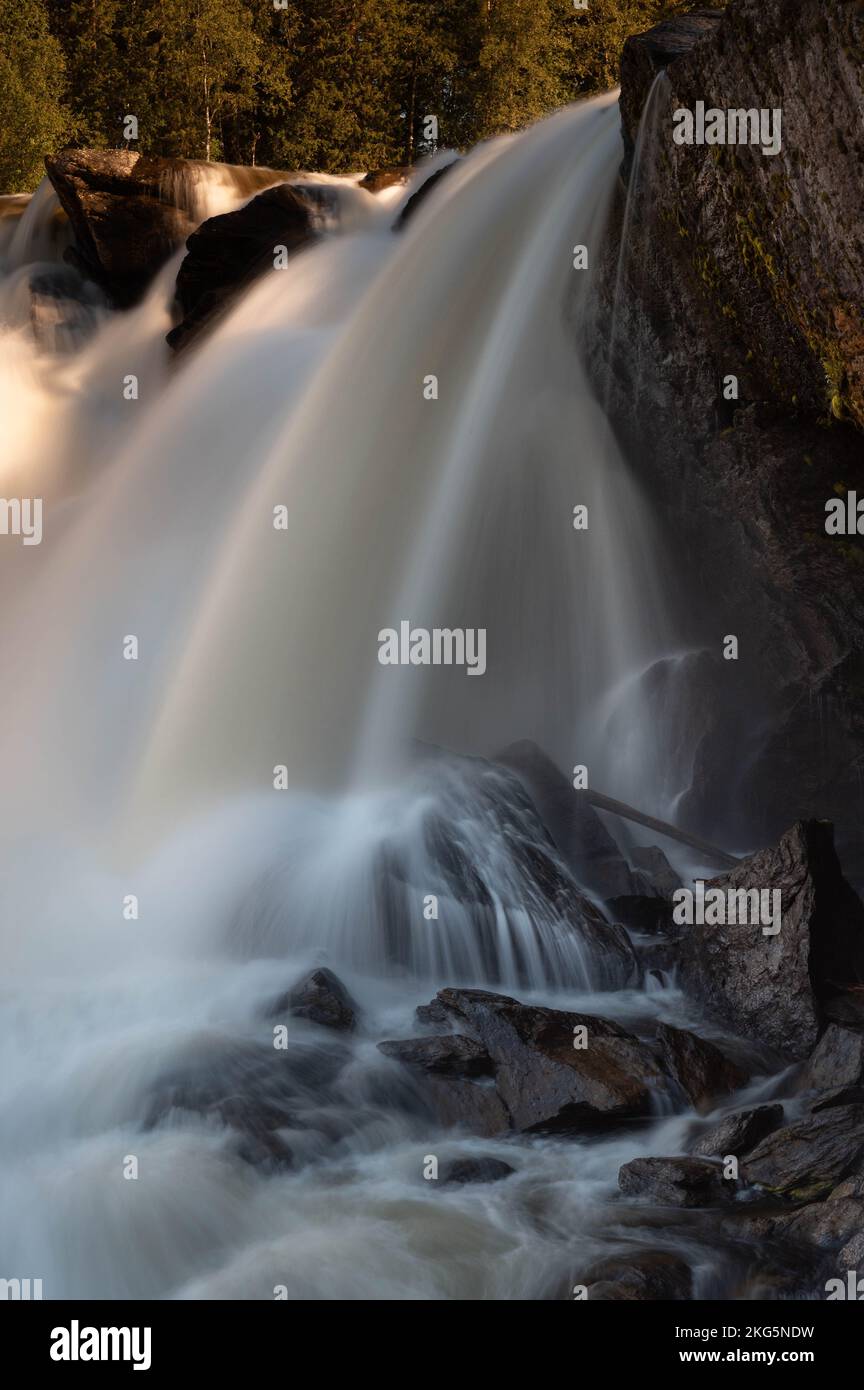 A vertical long exposure shot of a waterfall dropping from a rocky ...