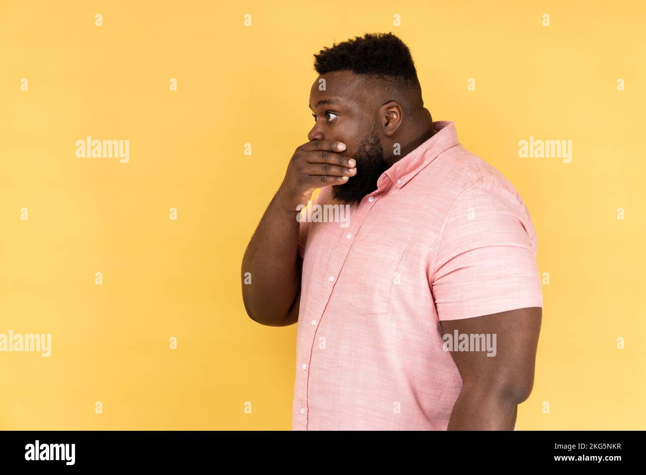 I won't tell. Side view of handsome man wearing pink shirt covering ...