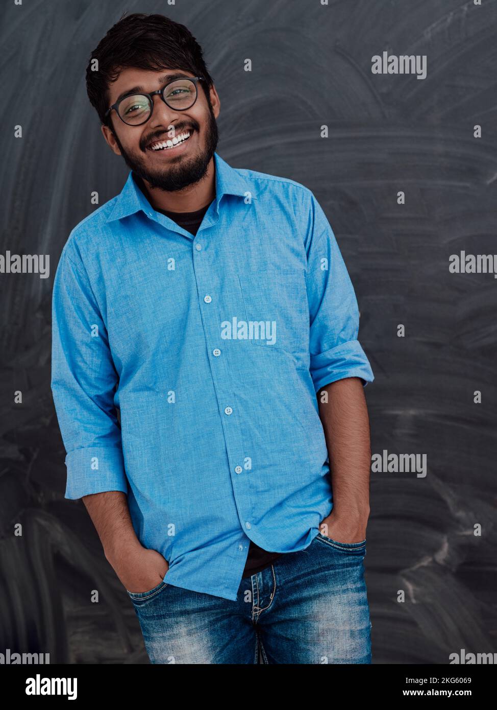 Indian smiling young student in blue shirt and glasses posing on school ...