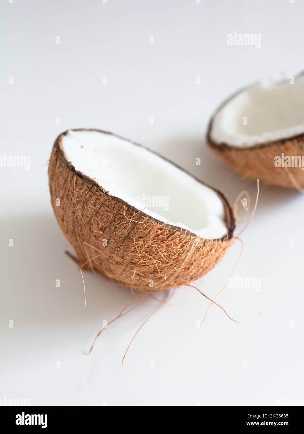 A vertical shot of a sliced coconut two halves isolated on white ...