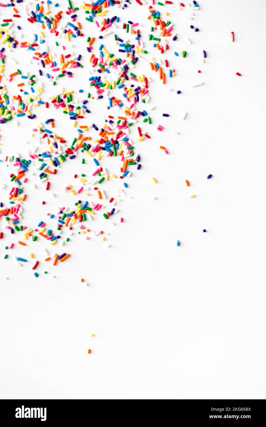 A vertical shot of rainbow sprinkles scattered on isolated white ...
