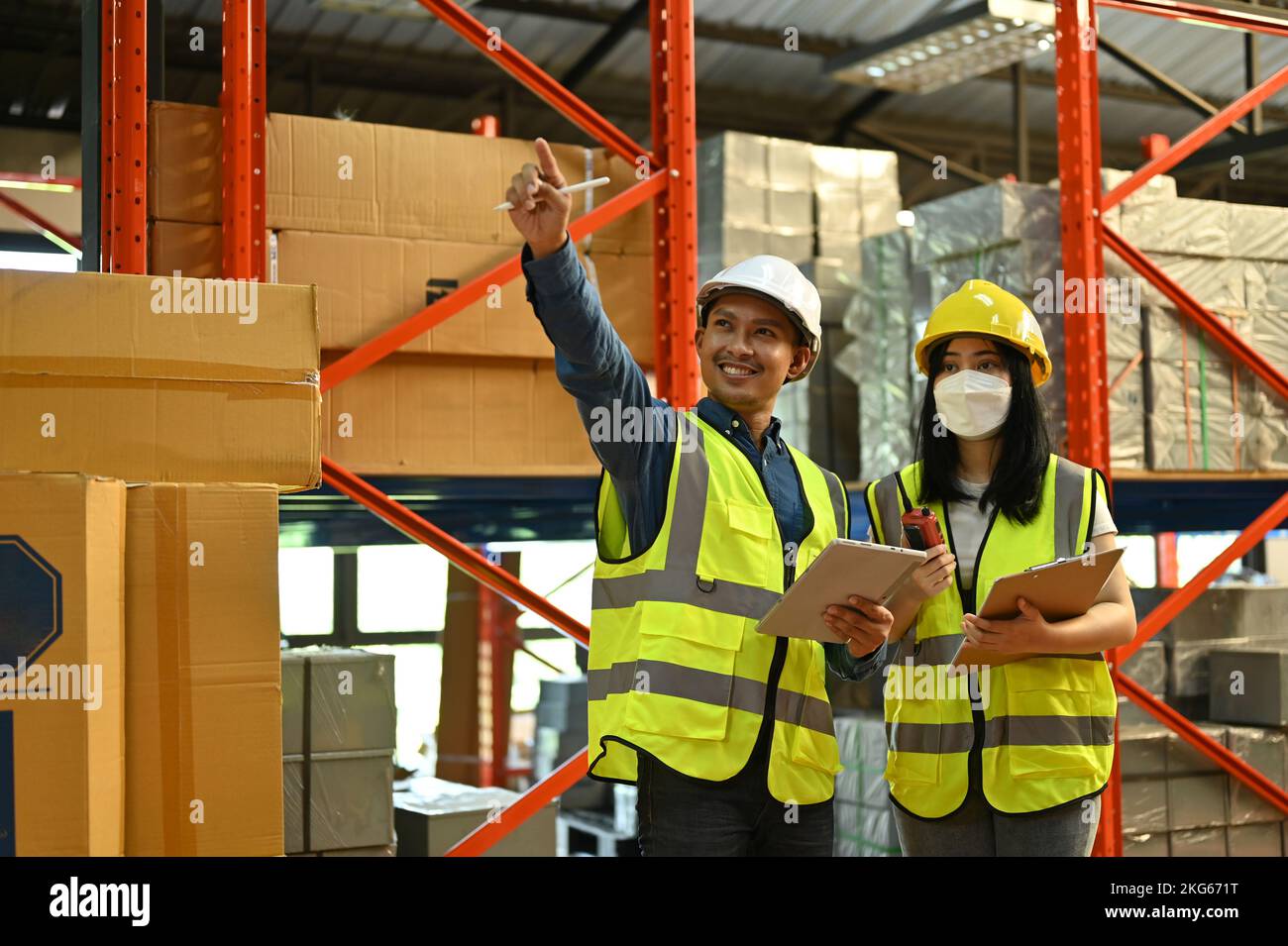 Two professional Asian warehouse workers are talking and discussing ...