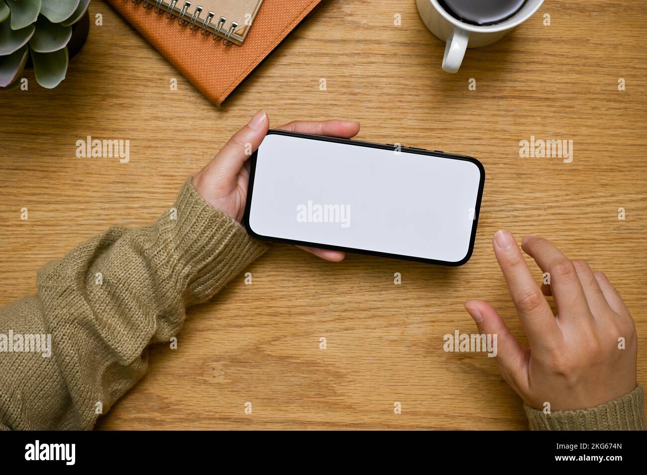 A smartphone white screen mockup in a horizontal position is in a woman ...