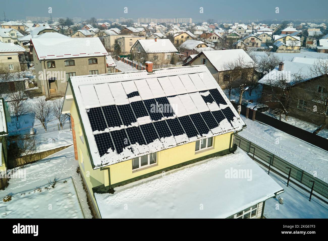 Aerial view of house roof with solar panels covered with snow melting ...