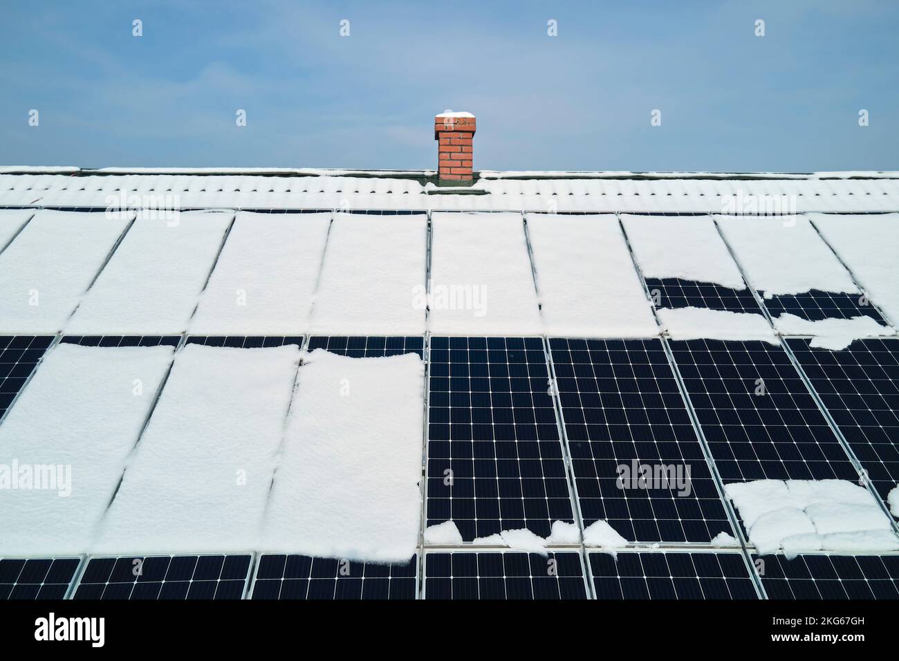 Aerial view of house roof with solar panels covered with snow melting ...